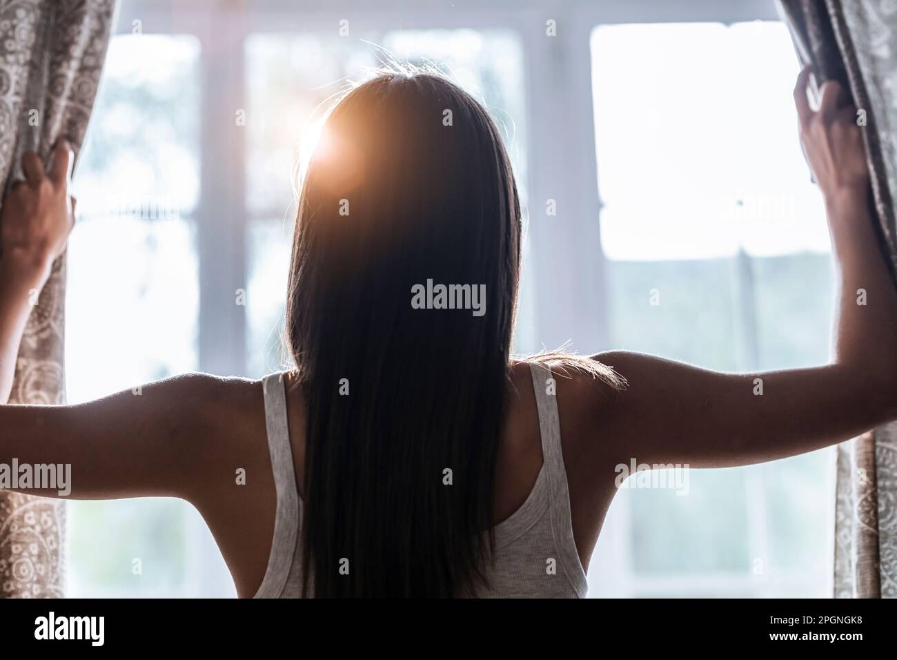 Woman opening curtains at the window Stock Photo - Alamy