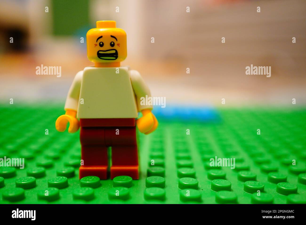 Isolated Lego figurine standing on green grass, exhibiting a shocked ...