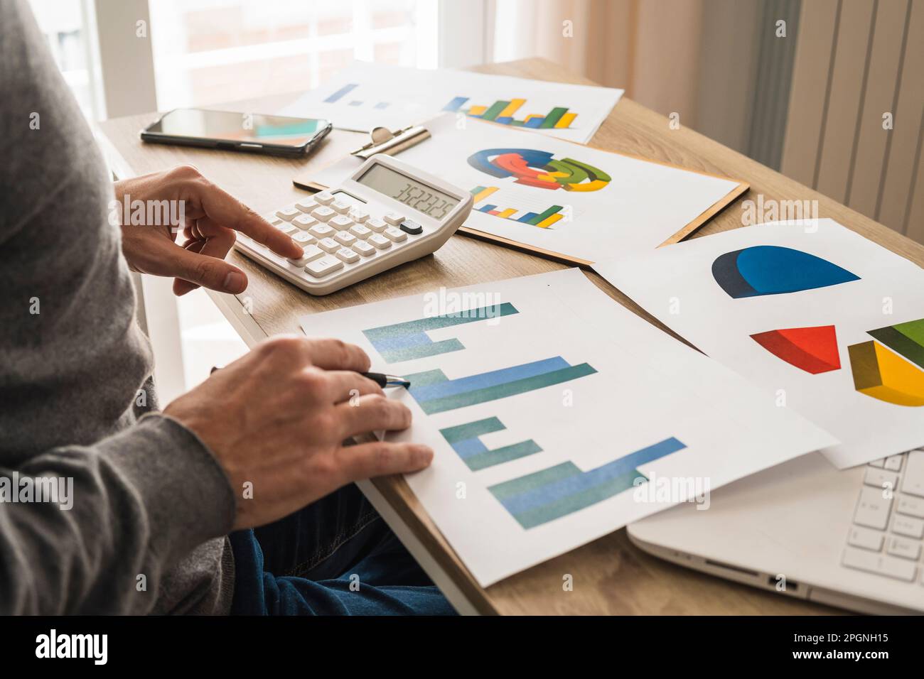 Businessman doing calculations with graphs at desk in office Stock ...