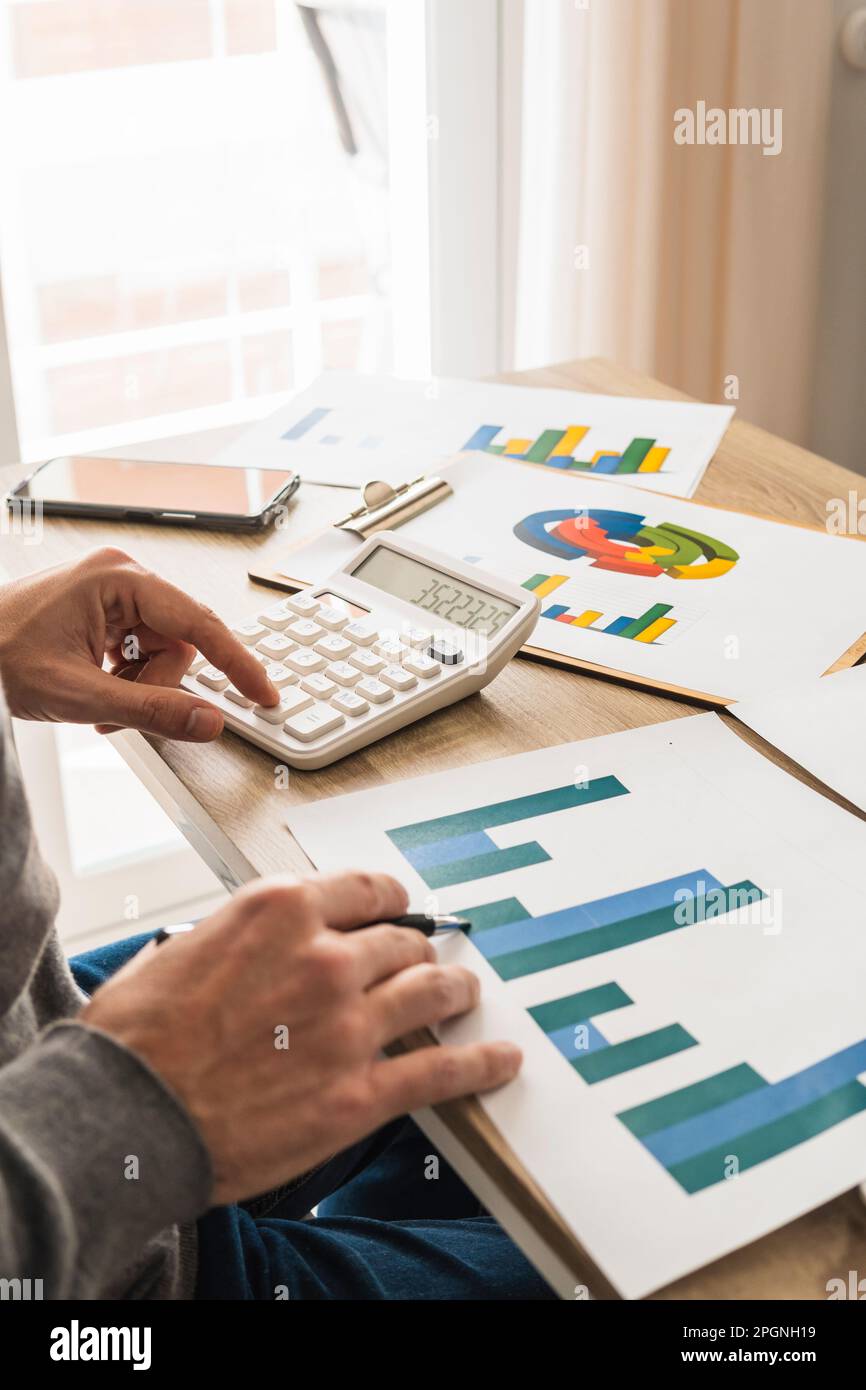 Hands of businessman examining graphs and doing calculations in office ...