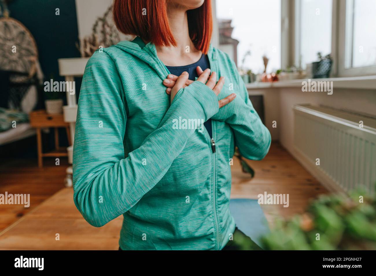 Woman with hands on chest doing breathing exercise at home Stock Photo ...