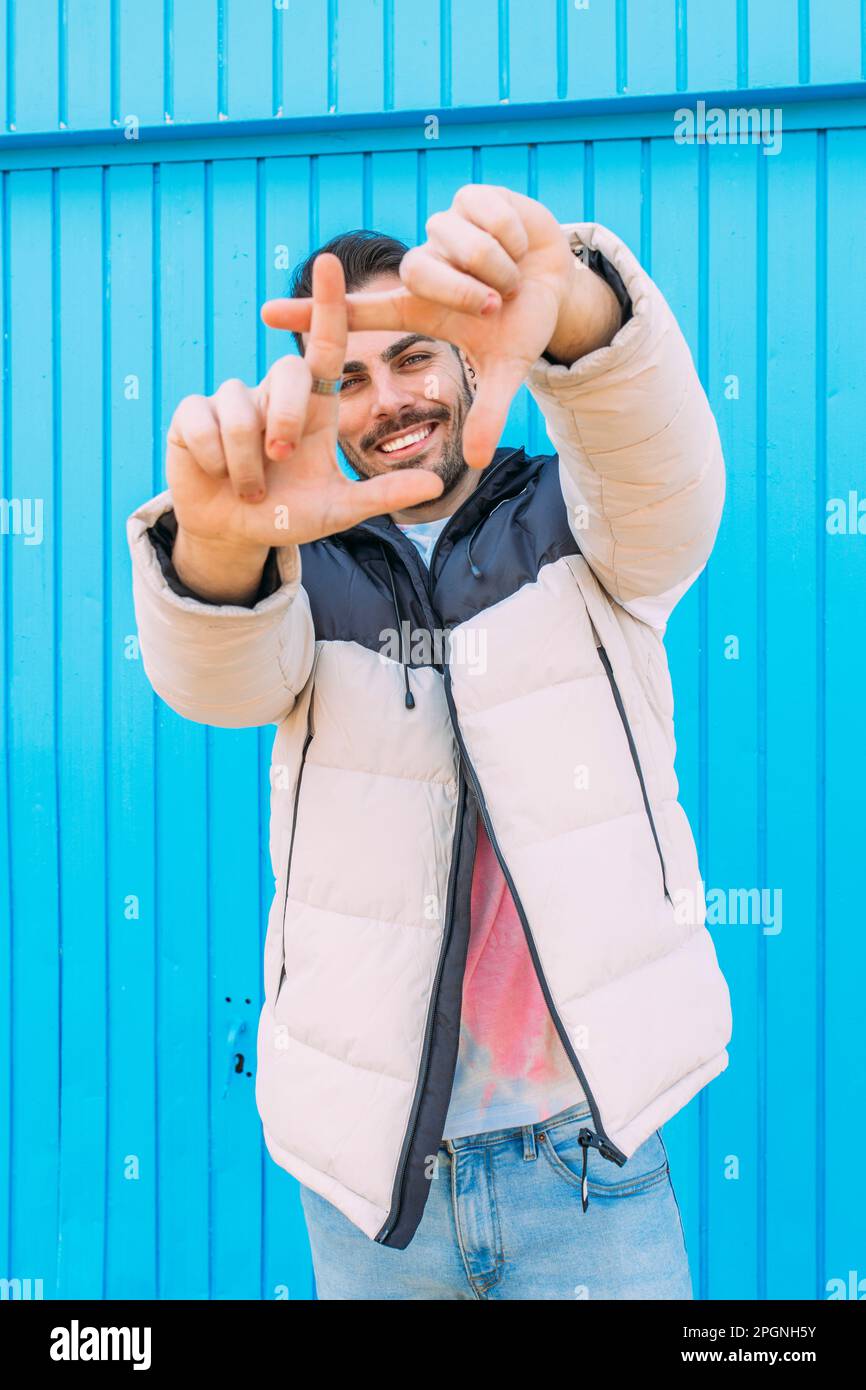 Smiling man making finger frame standing in front of blue wall Stock ...