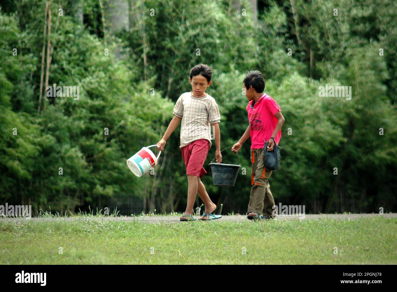 Children carry plastic buckets and have a conversation as they are ...