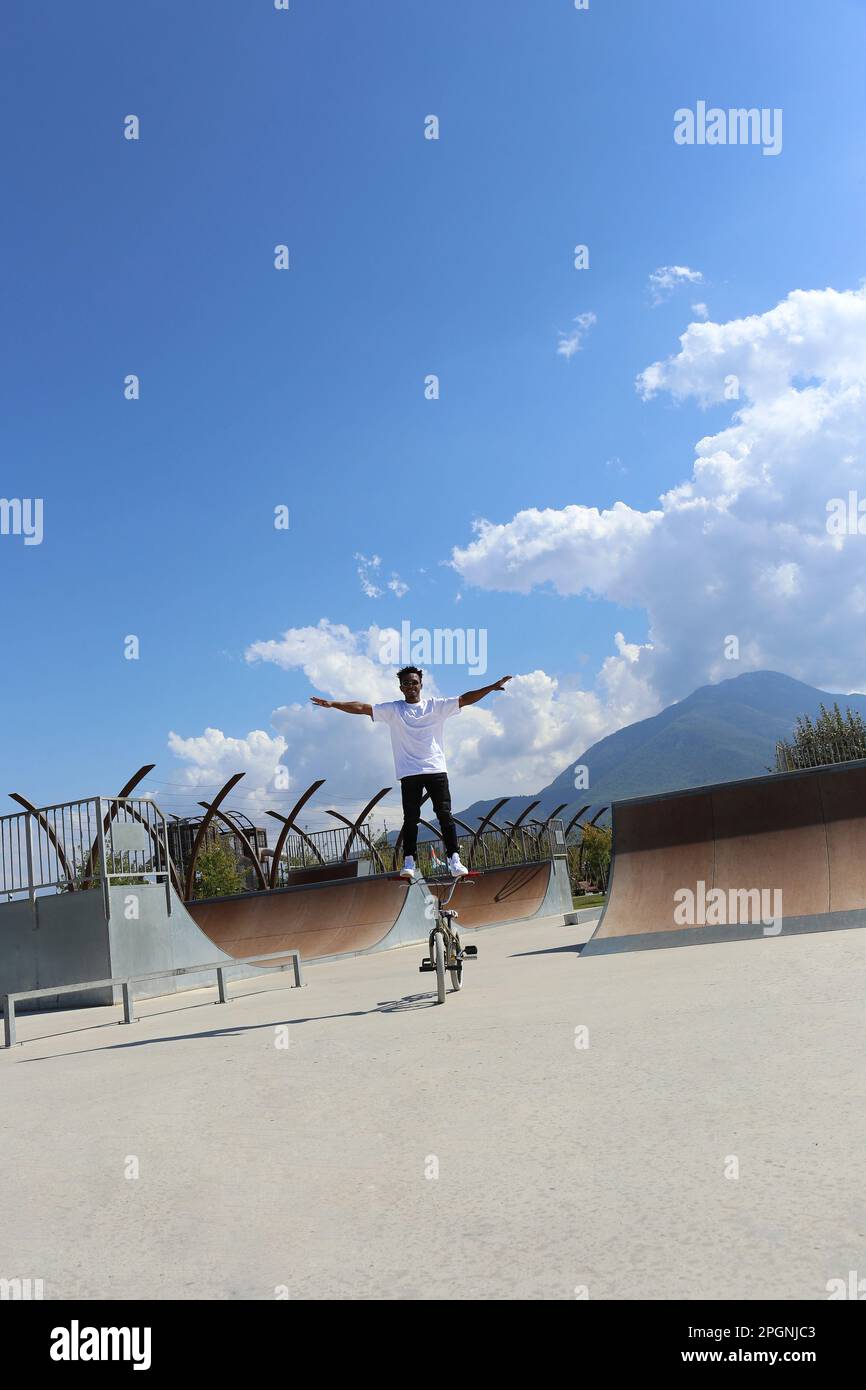Man standing on BMX bike with arms outstretched at skatepark Stock ...