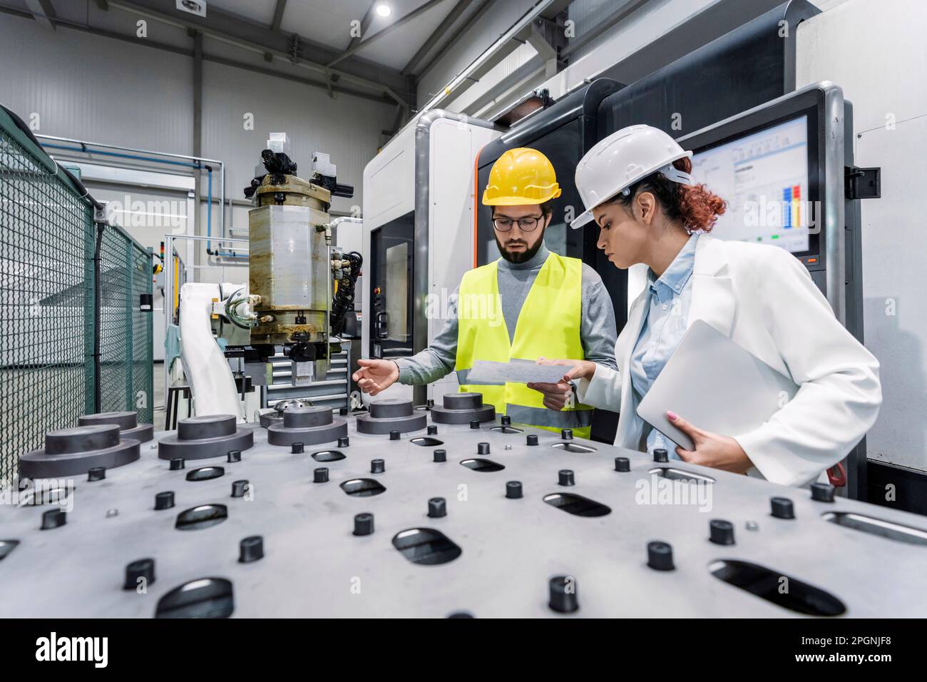 Engineer with colleague analyzing machine parts in factory Stock Photo - Alamy