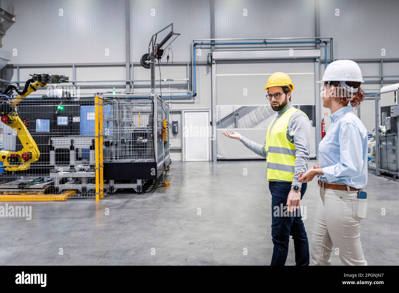 Engineers wearing hardhats discussing in factory Stock Photo - Alamy