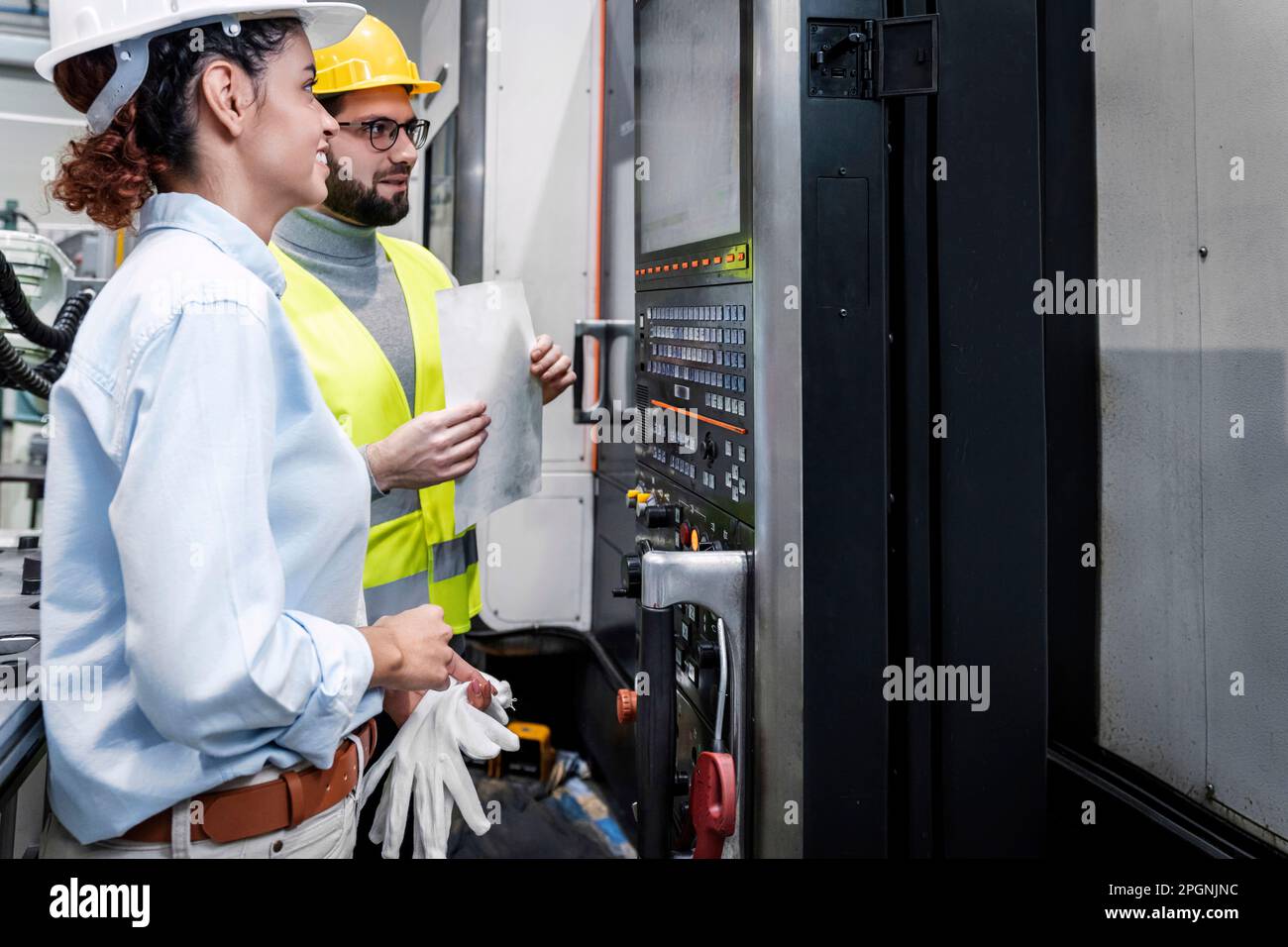 Smiling engineers looking at control panel screen in factory Stock ...