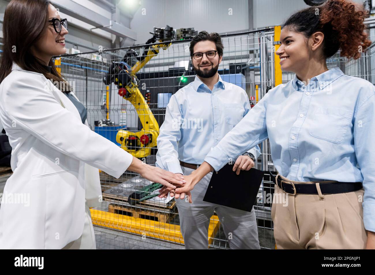 Smiling business people stacking hands in factory Stock Photo - Alamy