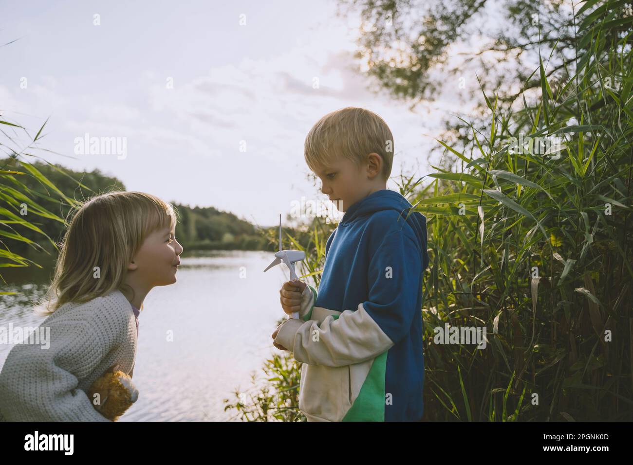 Boy and girl playing with wind turbine model near lake Stock Photo - Alamy