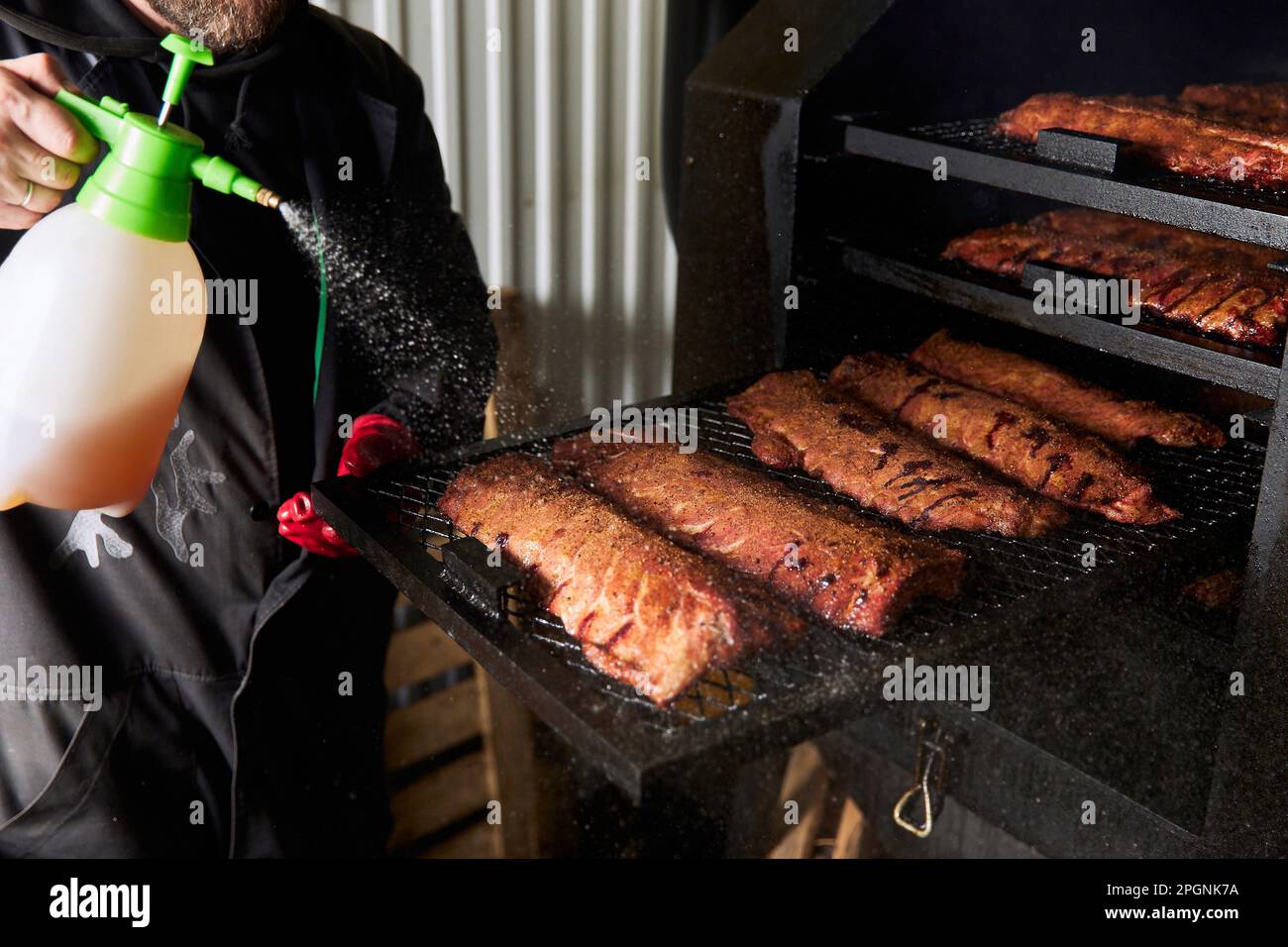Chef spraying on juicy barbecue meat Stock Photo - Alamy