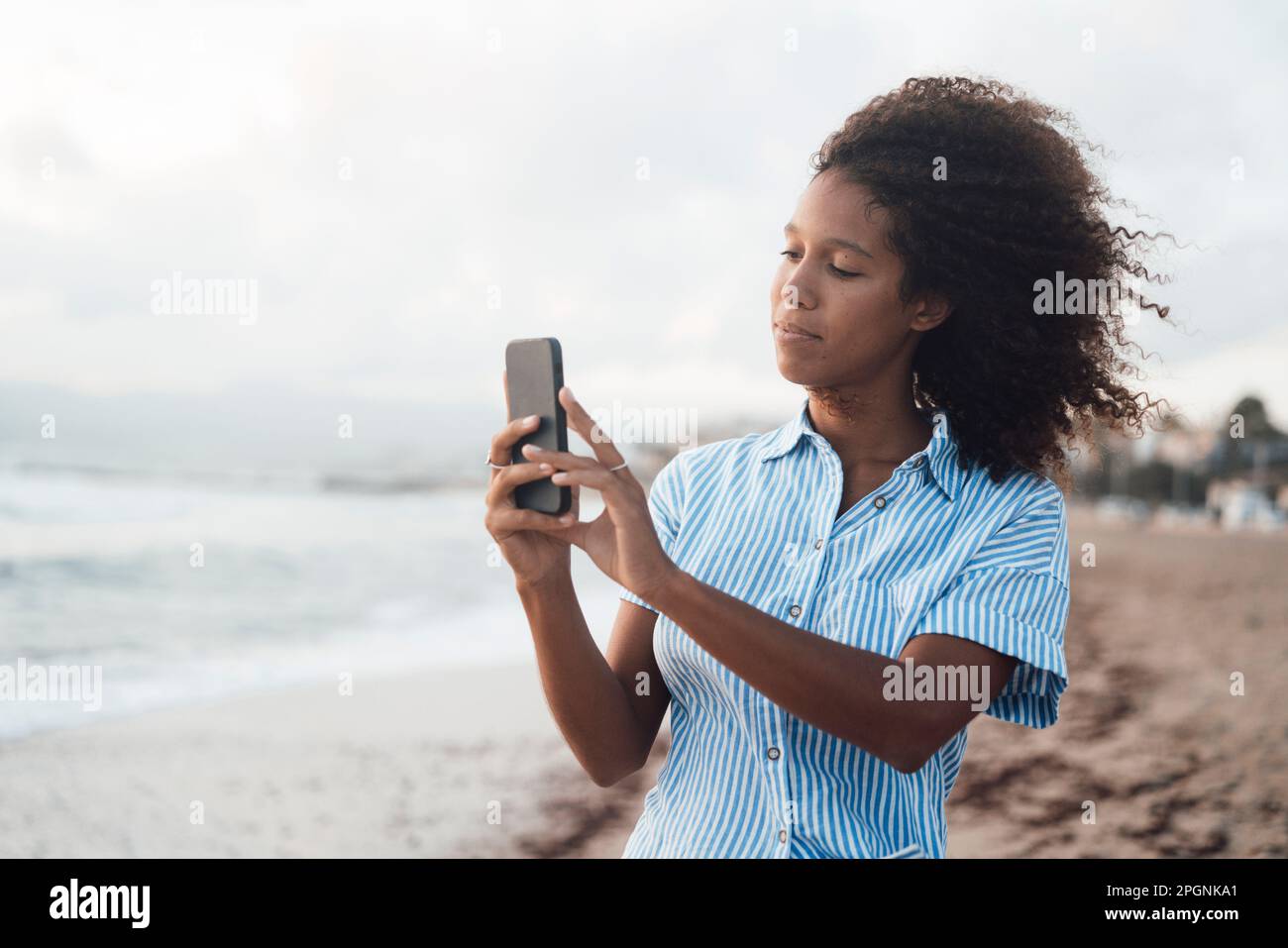 Young woman photographing through smart phone at beach Stock Photo - Alamy