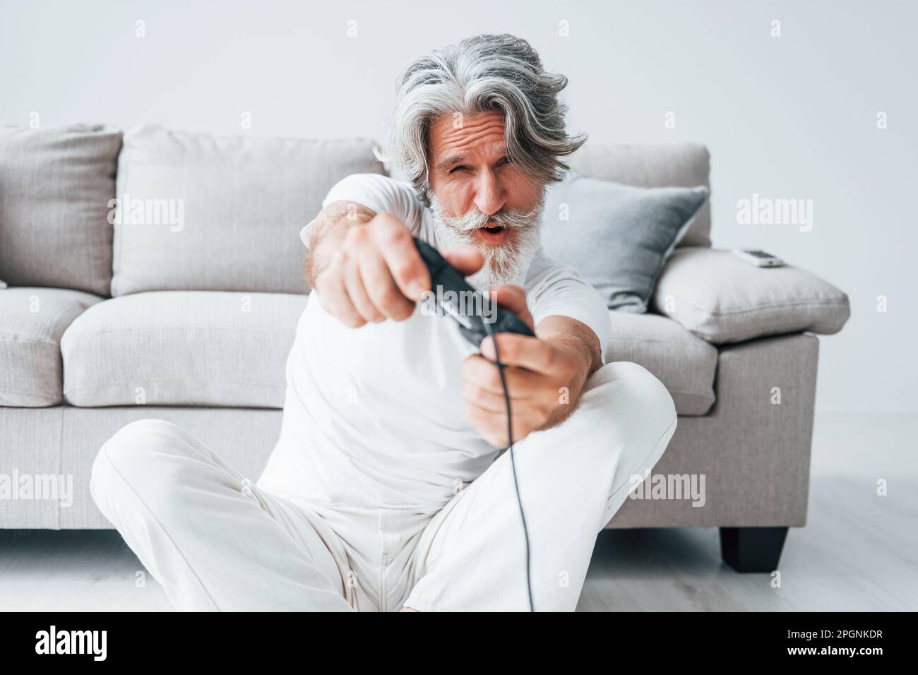 Plays video game by using controller. Senior stylish modern man with ...