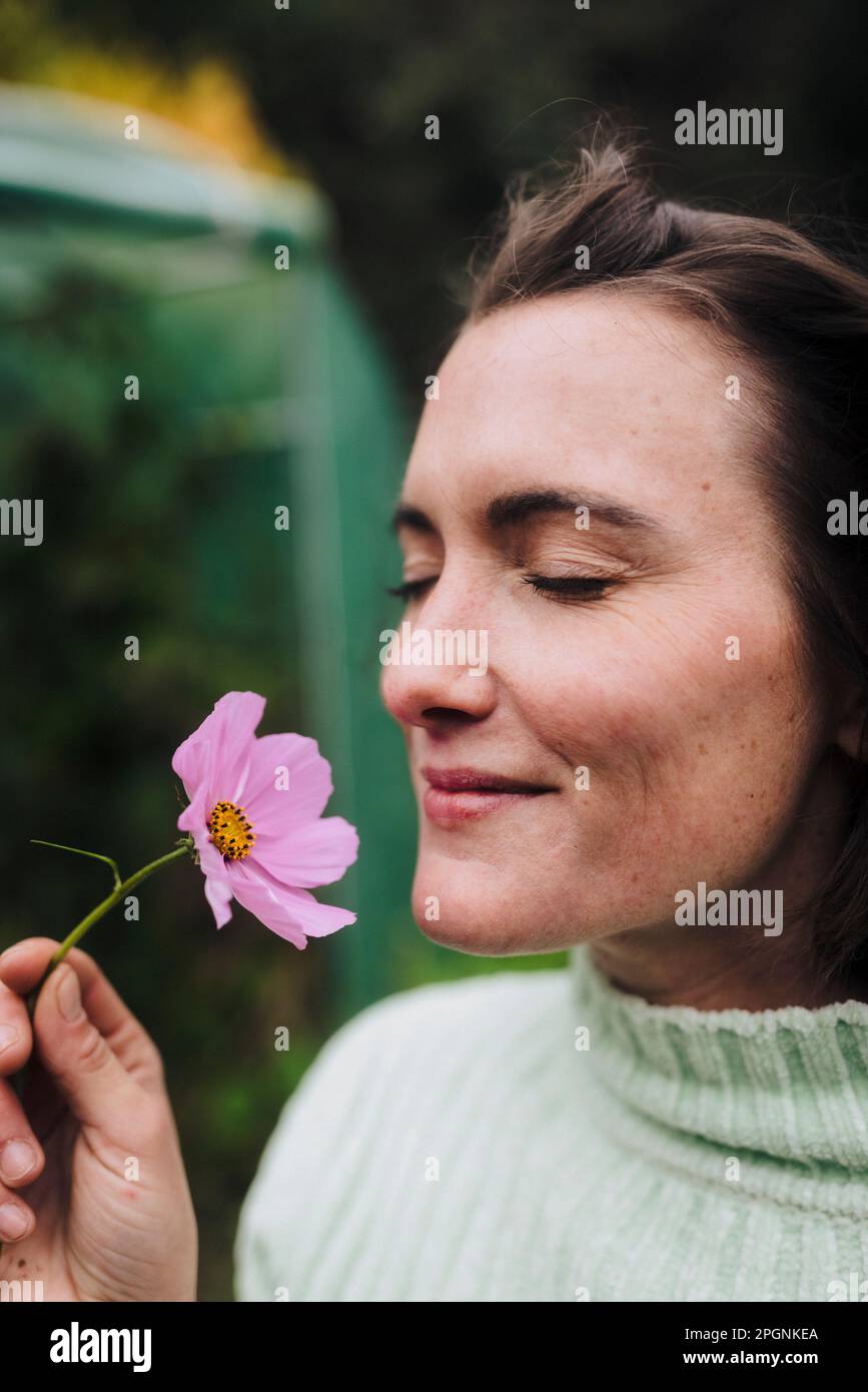 Woman smelling pink flower hi-res stock photography and images - Alamy