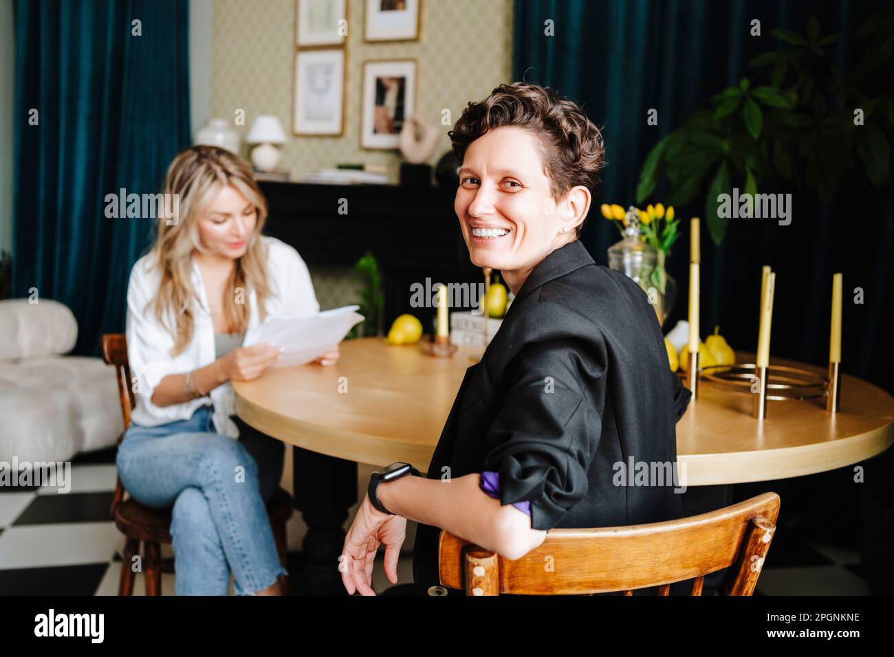 Happy producer sitting on chair with actress in background at film set ...