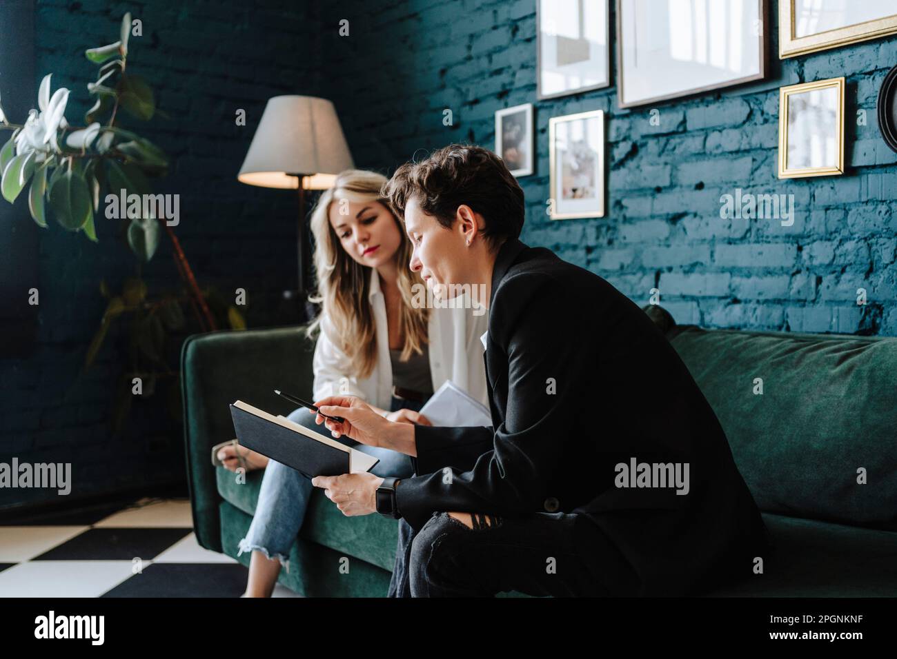 Producer and actress discussing together sitting on sofa at film set ...