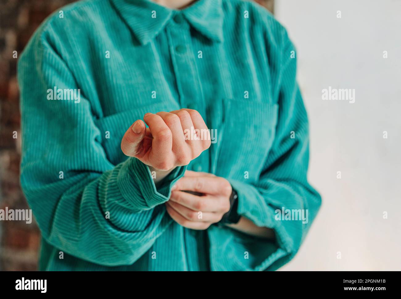 Woman buttoning wrist button of green shirt Stock Photo - Alamy