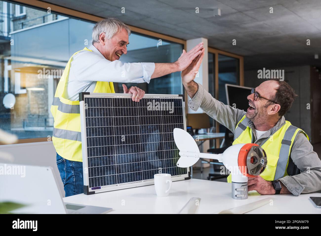 Happy engineers giving high-five at office Stock Photo - Alamy