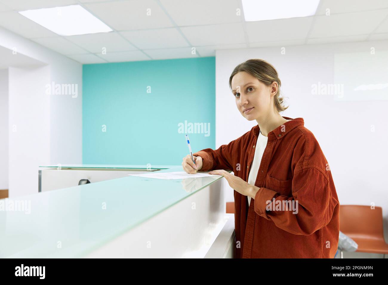 Woman filling form at reception Stock Photo - Alamy