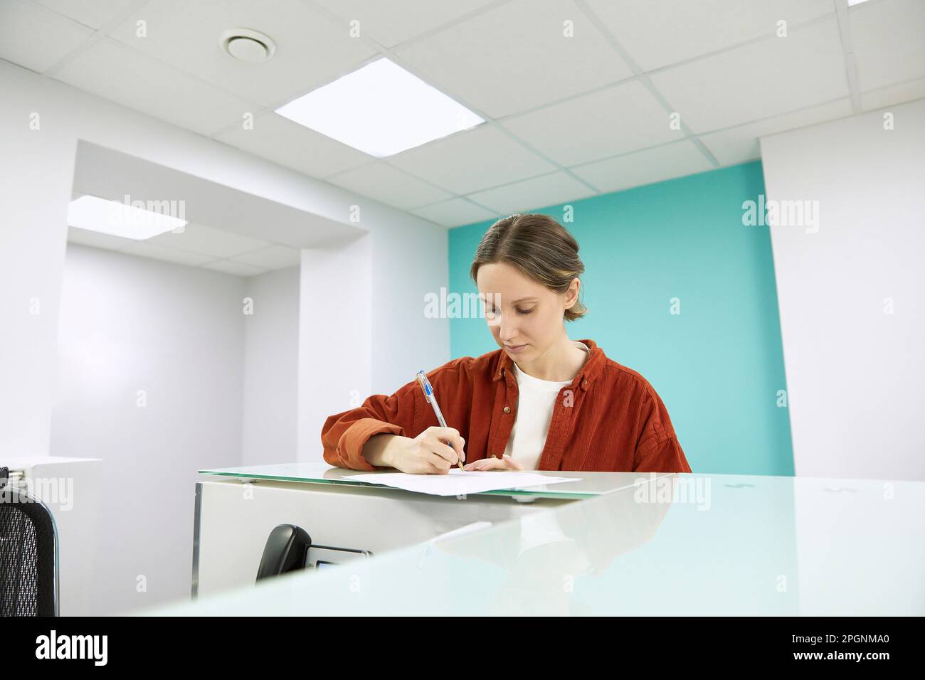 Woman filling form at reception in medical clinic Stock Photo - Alamy