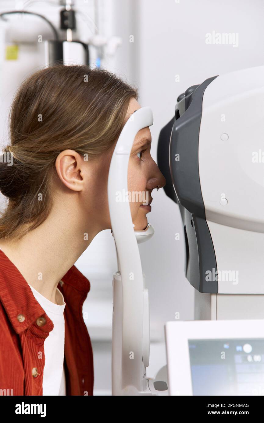 Patient doing eye check up through modern equipment at medical clinic ...
