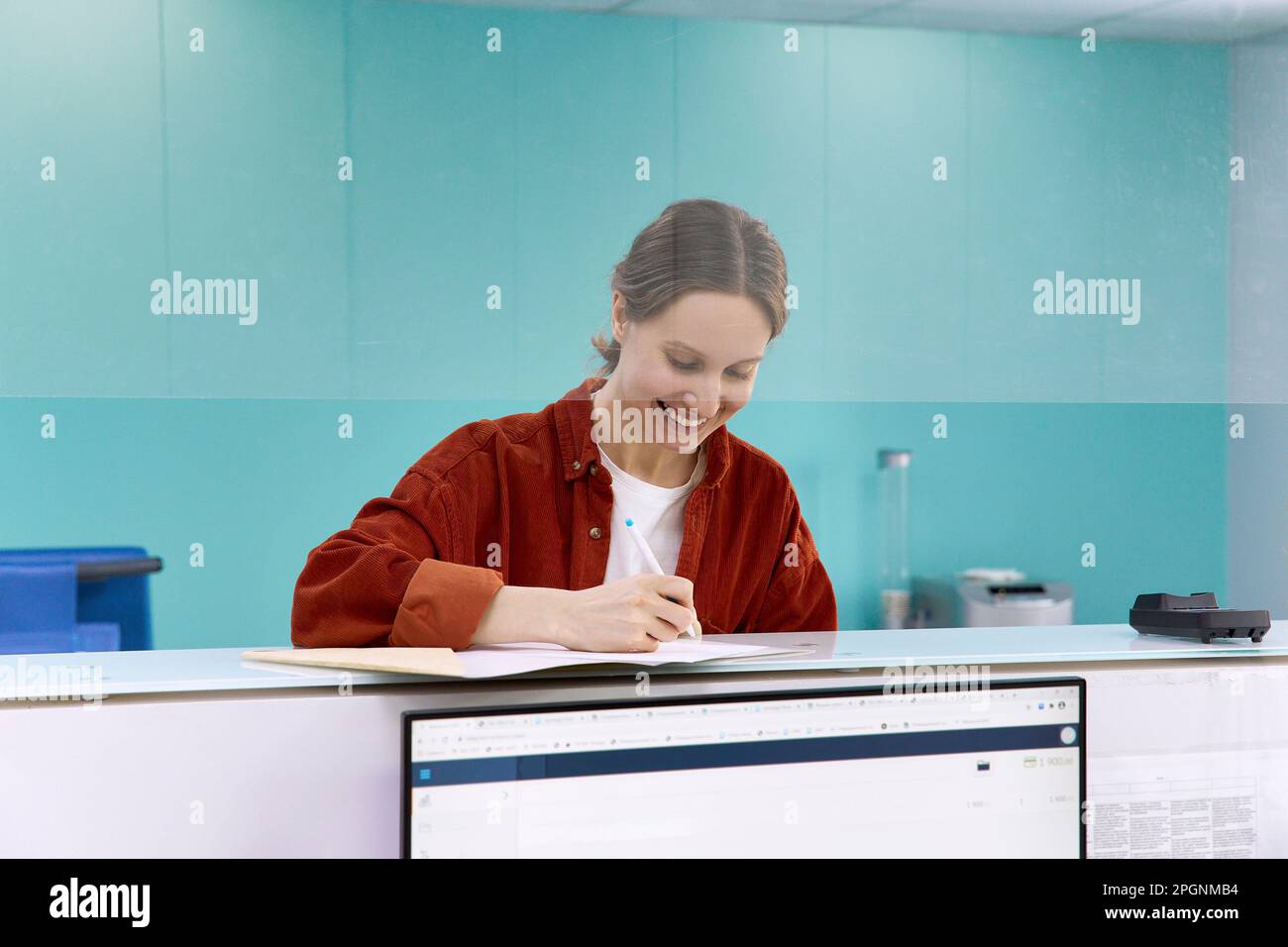 Smiling woman filling form at medical clinic Stock Photo - Alamy