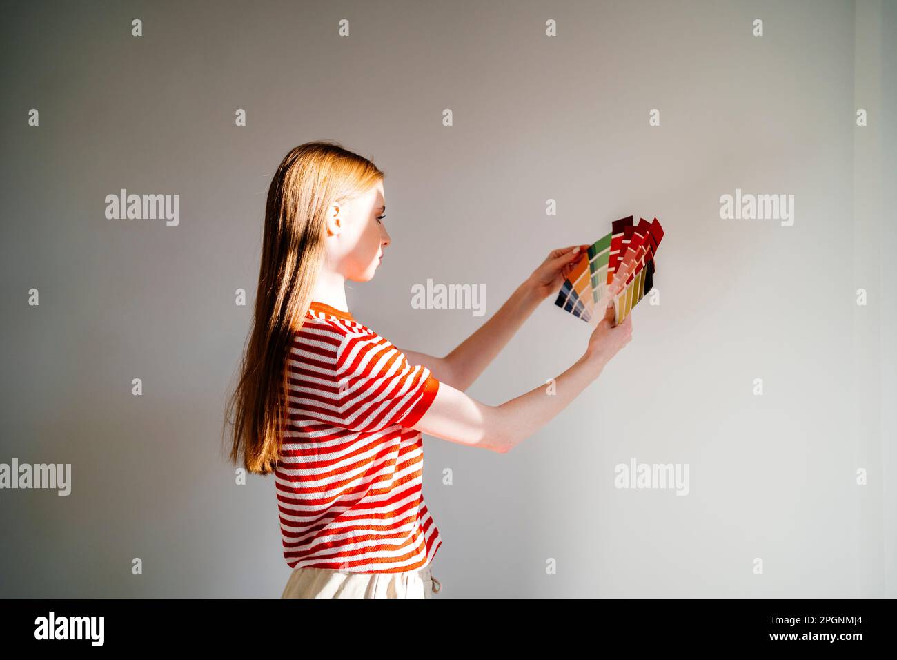 Teenage girl holding color swatch in front of white wall Stock Photo ...