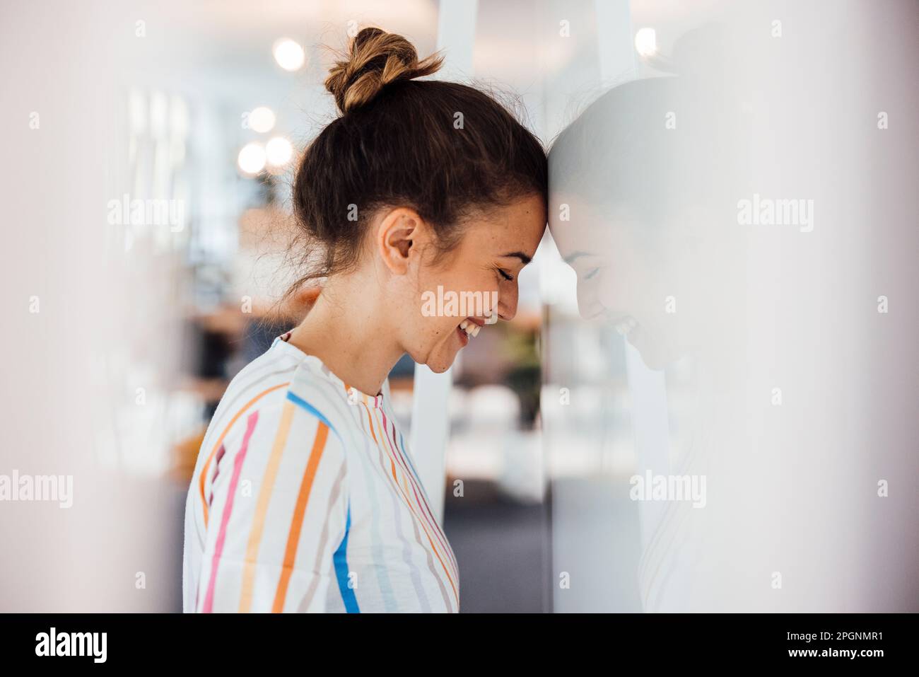 Happy businesswoman leaning forehead on wall in office Stock Photo - Alamy
