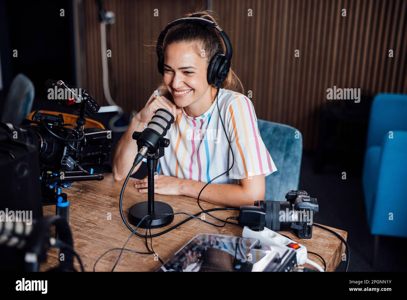 Happy influencer wearing headphones talking into microphone and ...