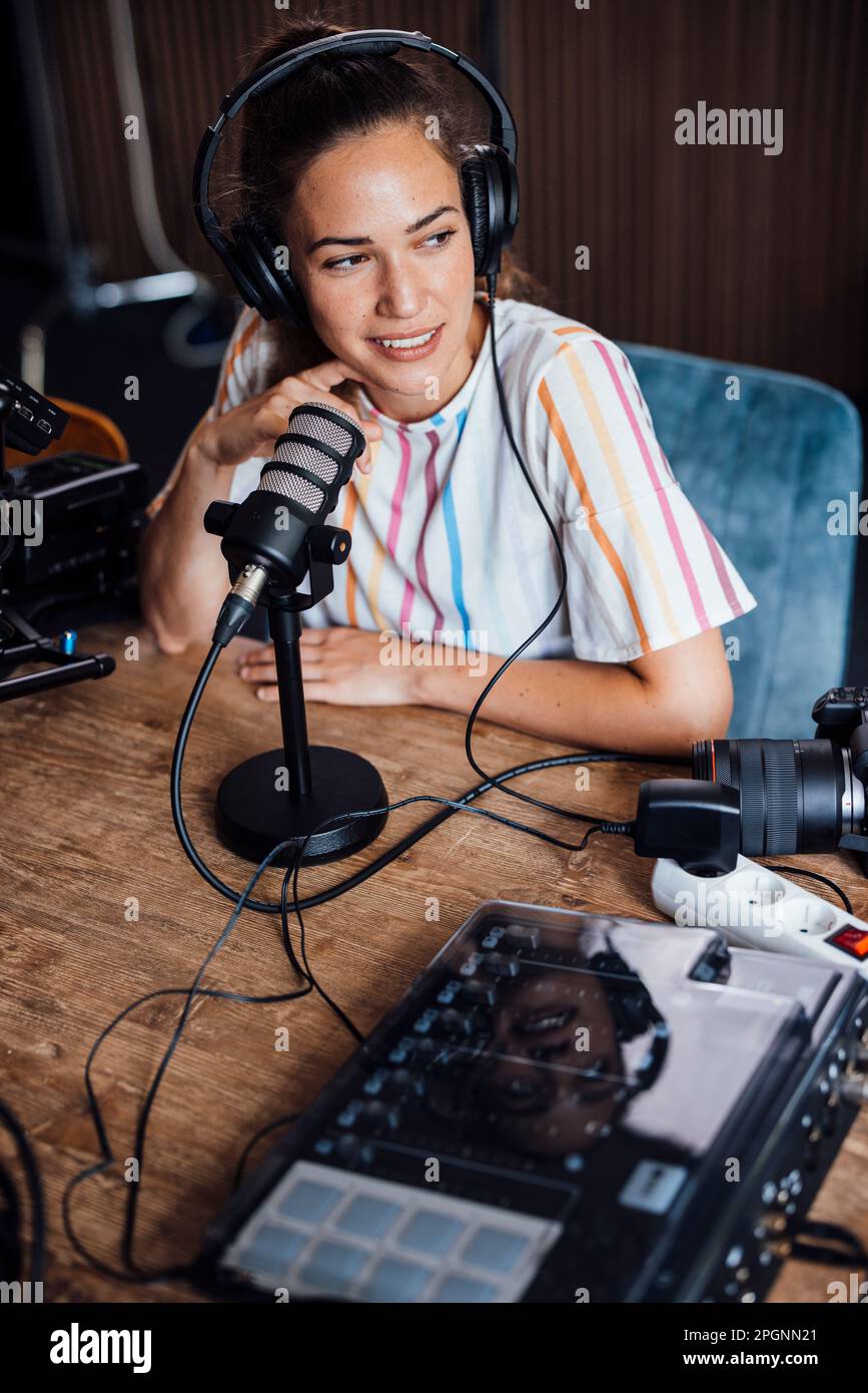 Young podcast artist wearing headphones talking into microphone at ...