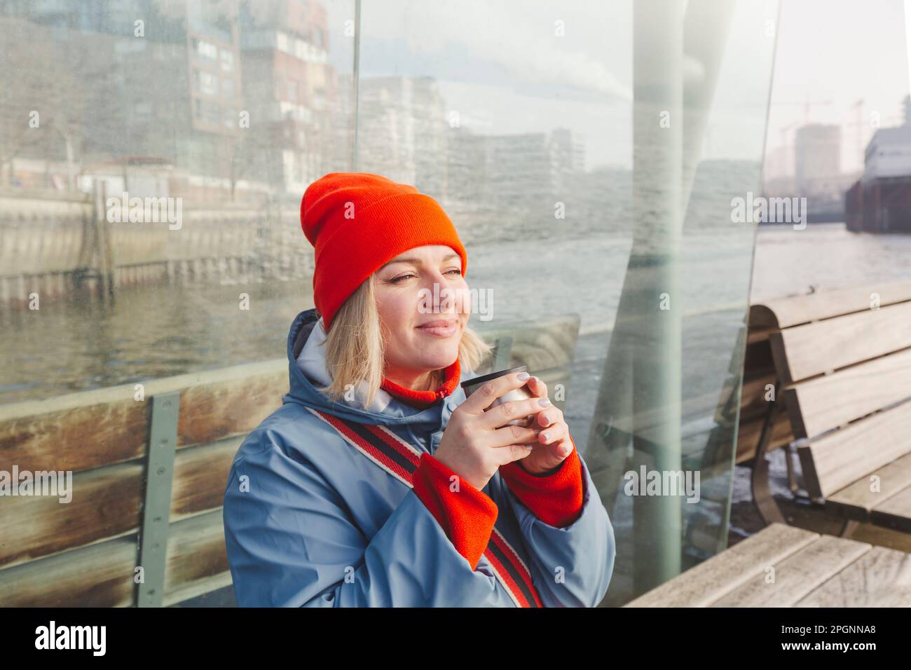 Woman drinking coffee sitting on bench at ferry terminal Stock Photo ...