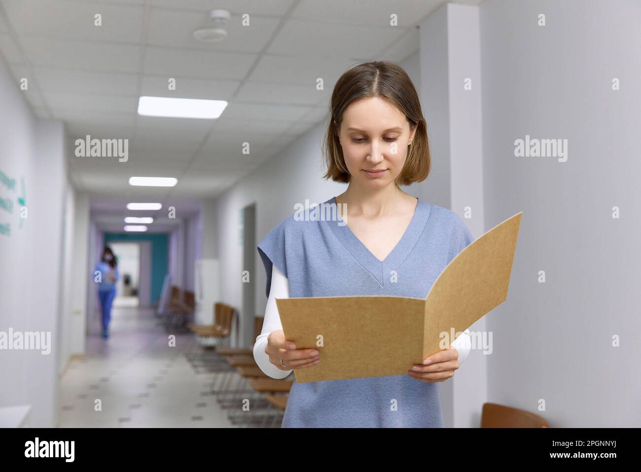 Patient reading file standing in corridor at hospital Stock Photo - Alamy