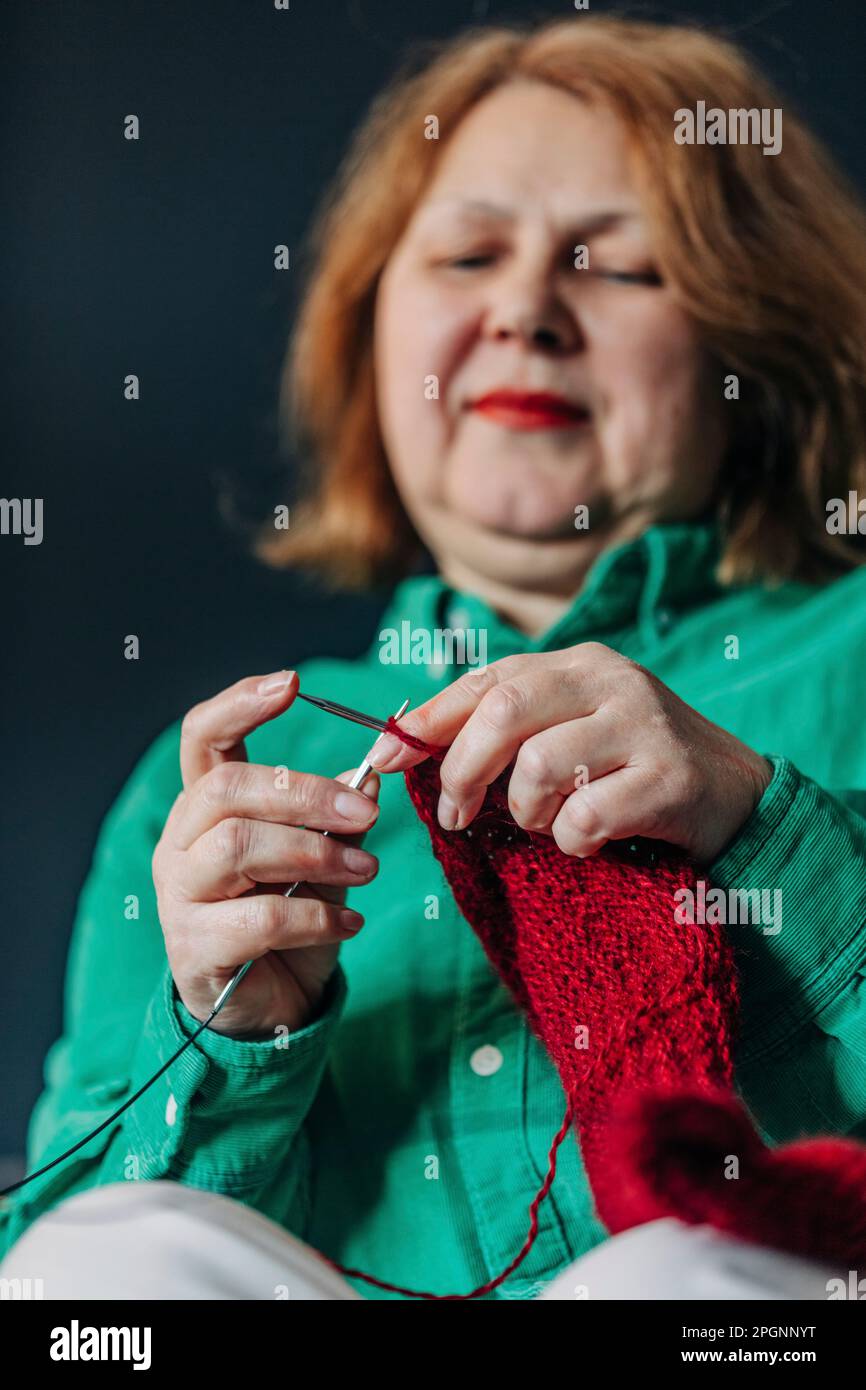 Senior woman knitting red sweater Stock Photo - Alamy