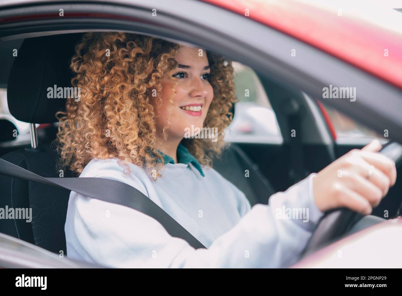 Smiling woman with curly hair driving car Stock Photo - Alamy