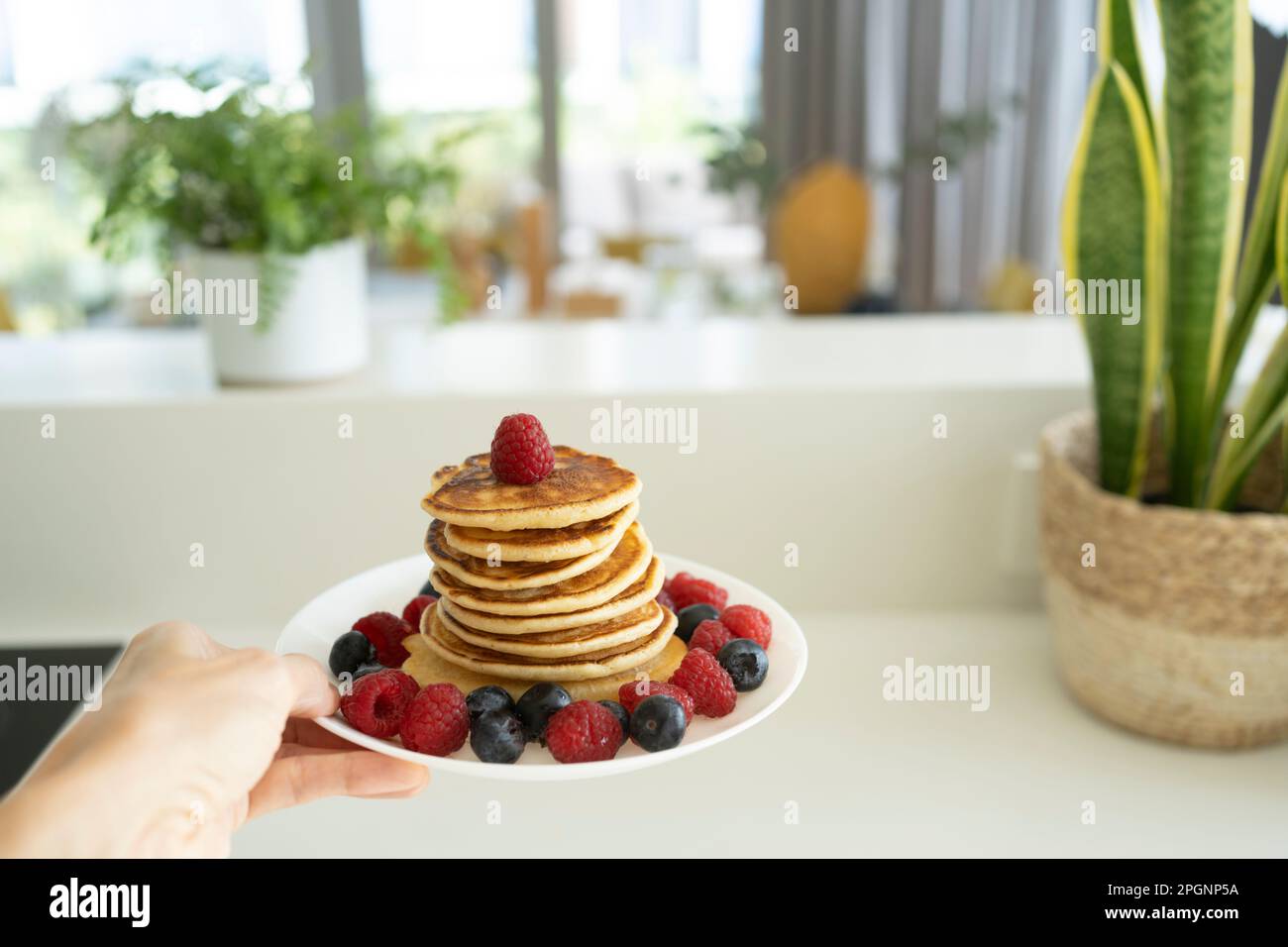 Hand holding stack of fresh pancakes on plate at home Stock Photo - Alamy
