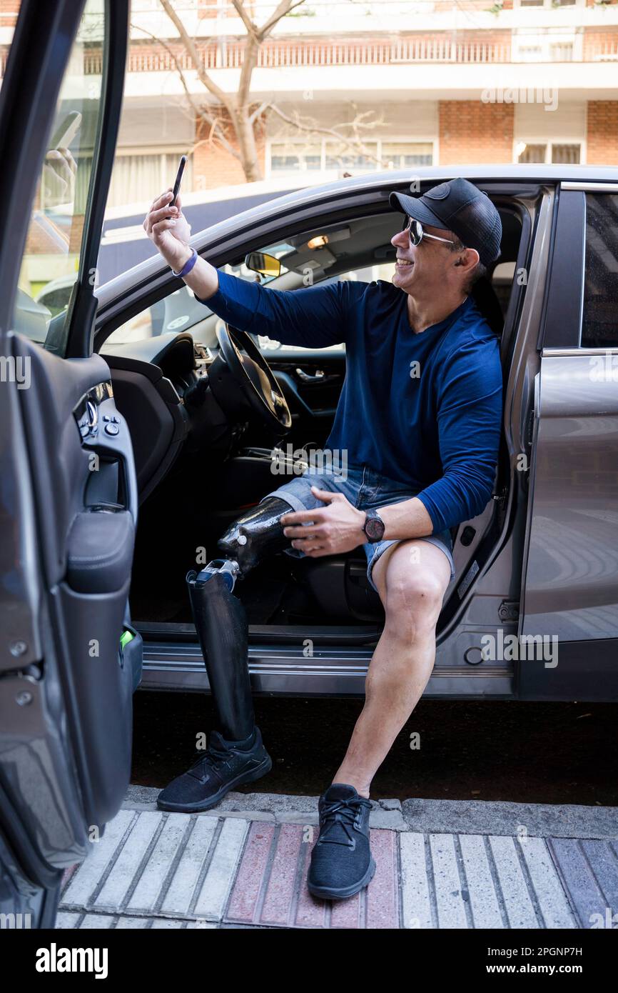 Smiling man with prosthetic leg taking selfie through smart phone ...