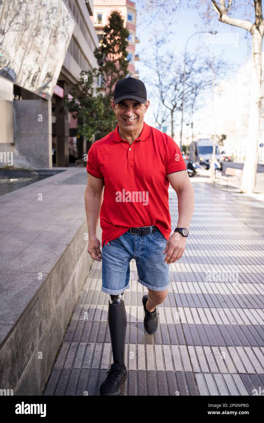 Smiling man with disability walking on sidewalk Stock Photo - Alamy