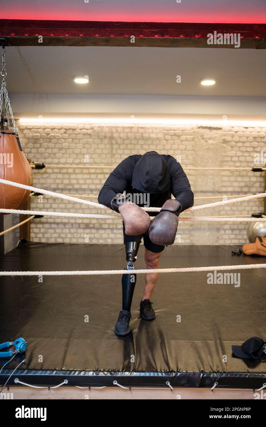 Mature man with prosthetic leg leaning on rope in boxing ring Stock ...