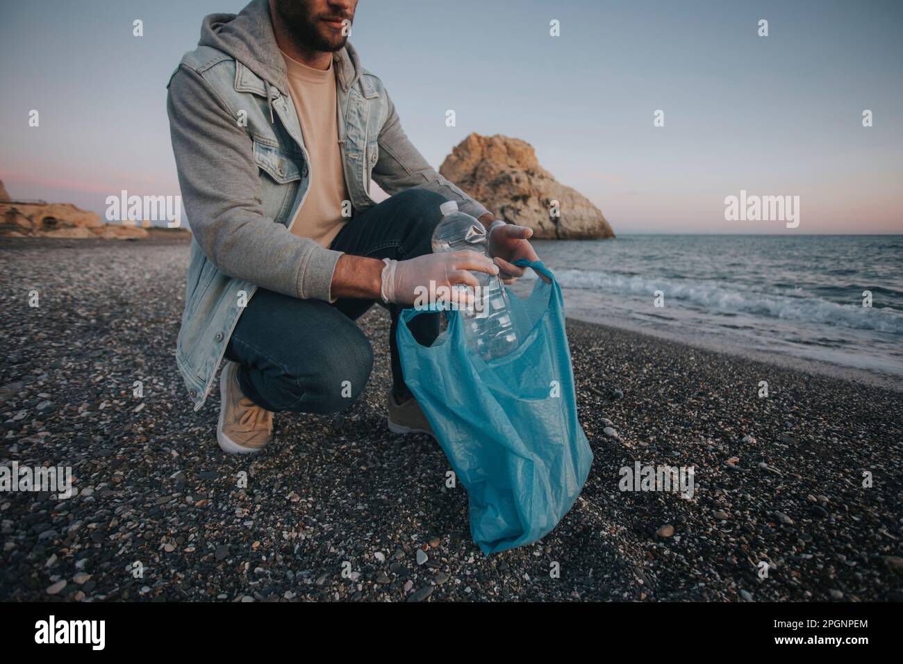 Man collecting trash from coastline at beach Stock Photo - Alamy