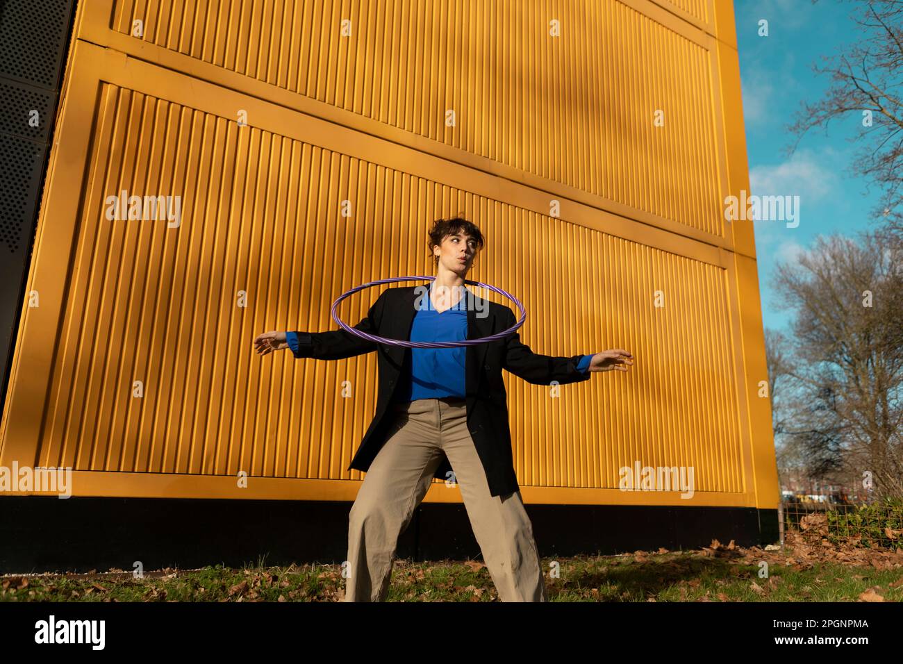 Woman playing with hula hoop in front of yellow container Stock Photo ...