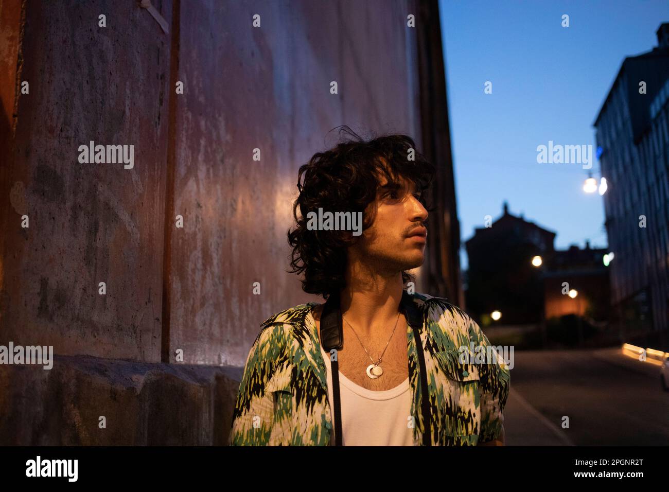 Contemplative young man standing by wall at dusk Stock Photo - Alamy