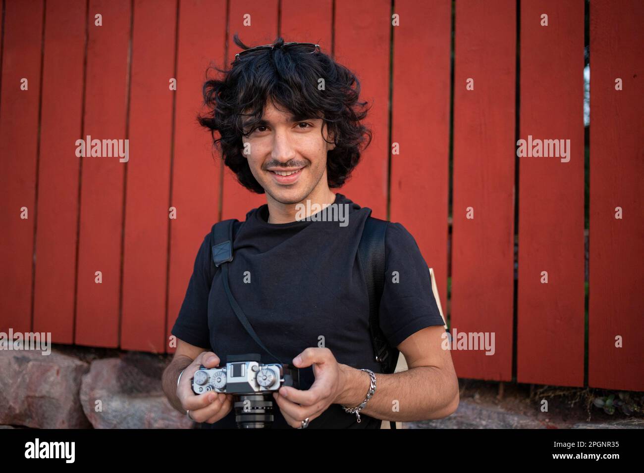 Happy man standing with camera in front of wall Stock Photo - Alamy