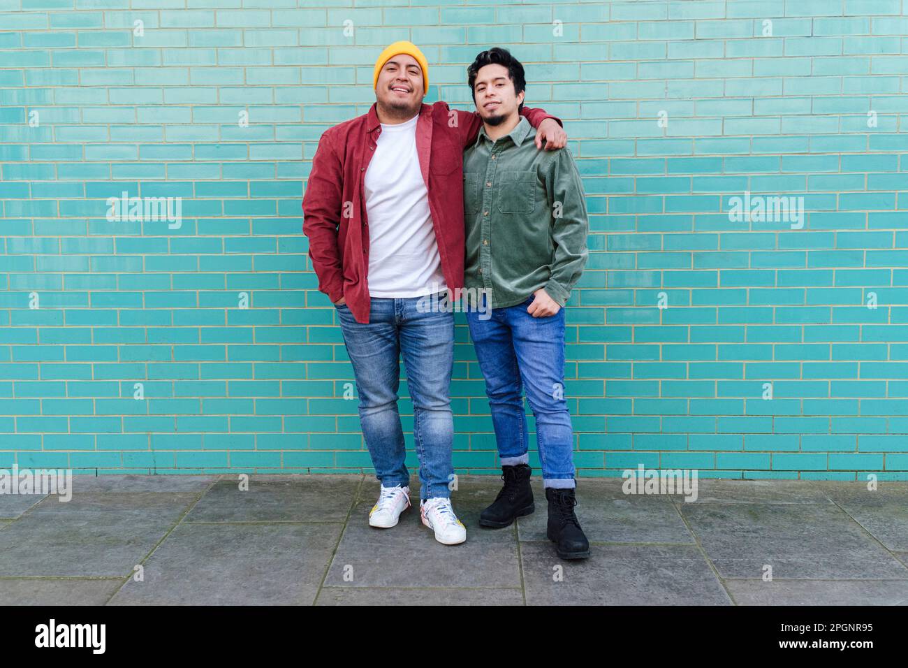 Happy brothers standing together in front of turquoise brick wall Stock ...