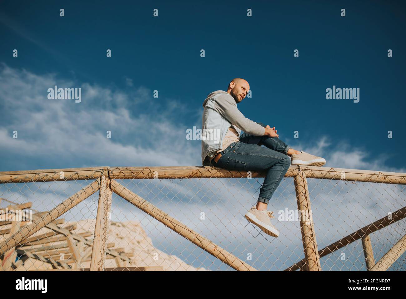 Man sitting on fence under sky Stock Photo - Alamy