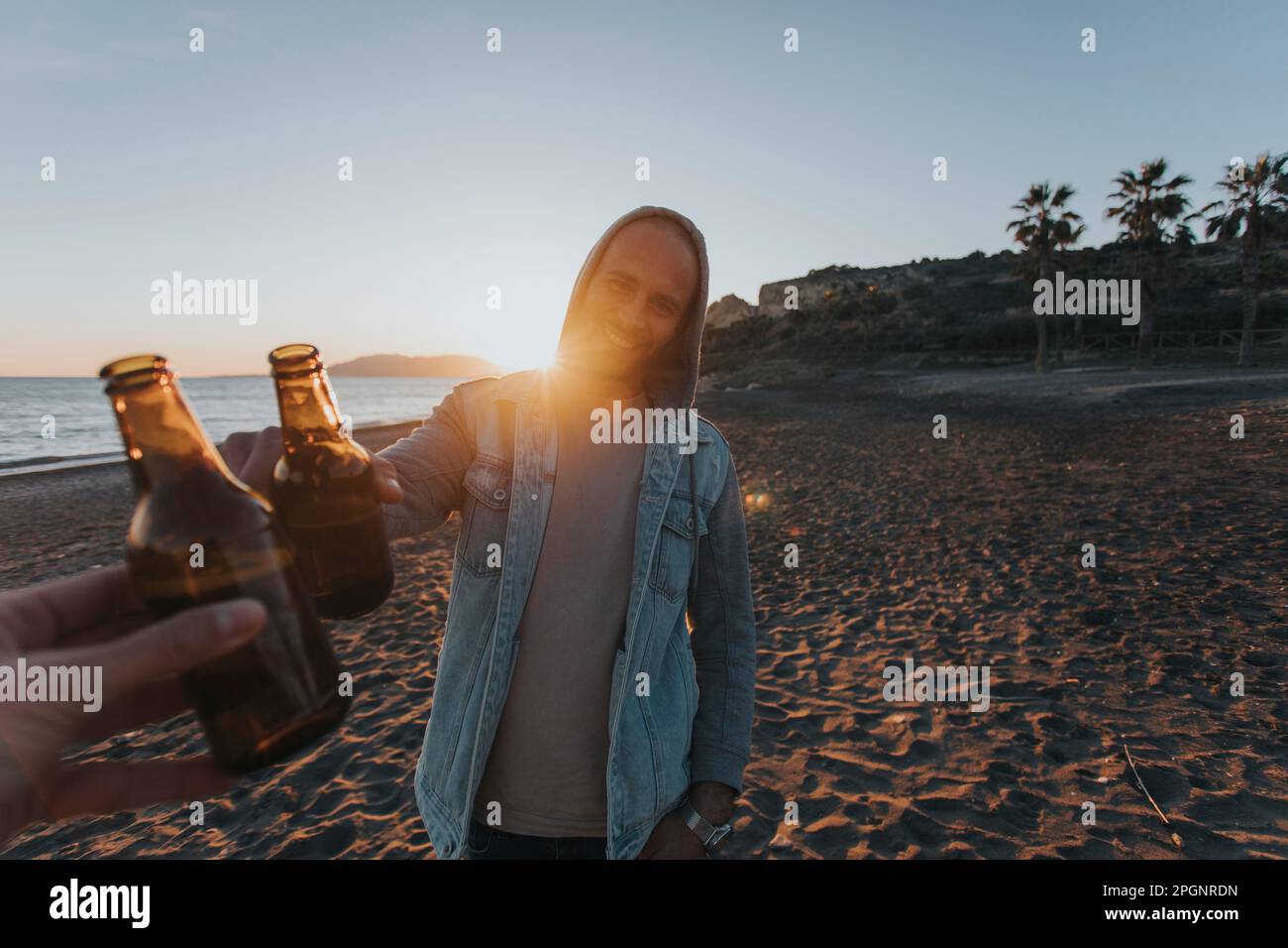 Happy man toasting beer bottle with friend at sunset Stock Photo - Alamy
