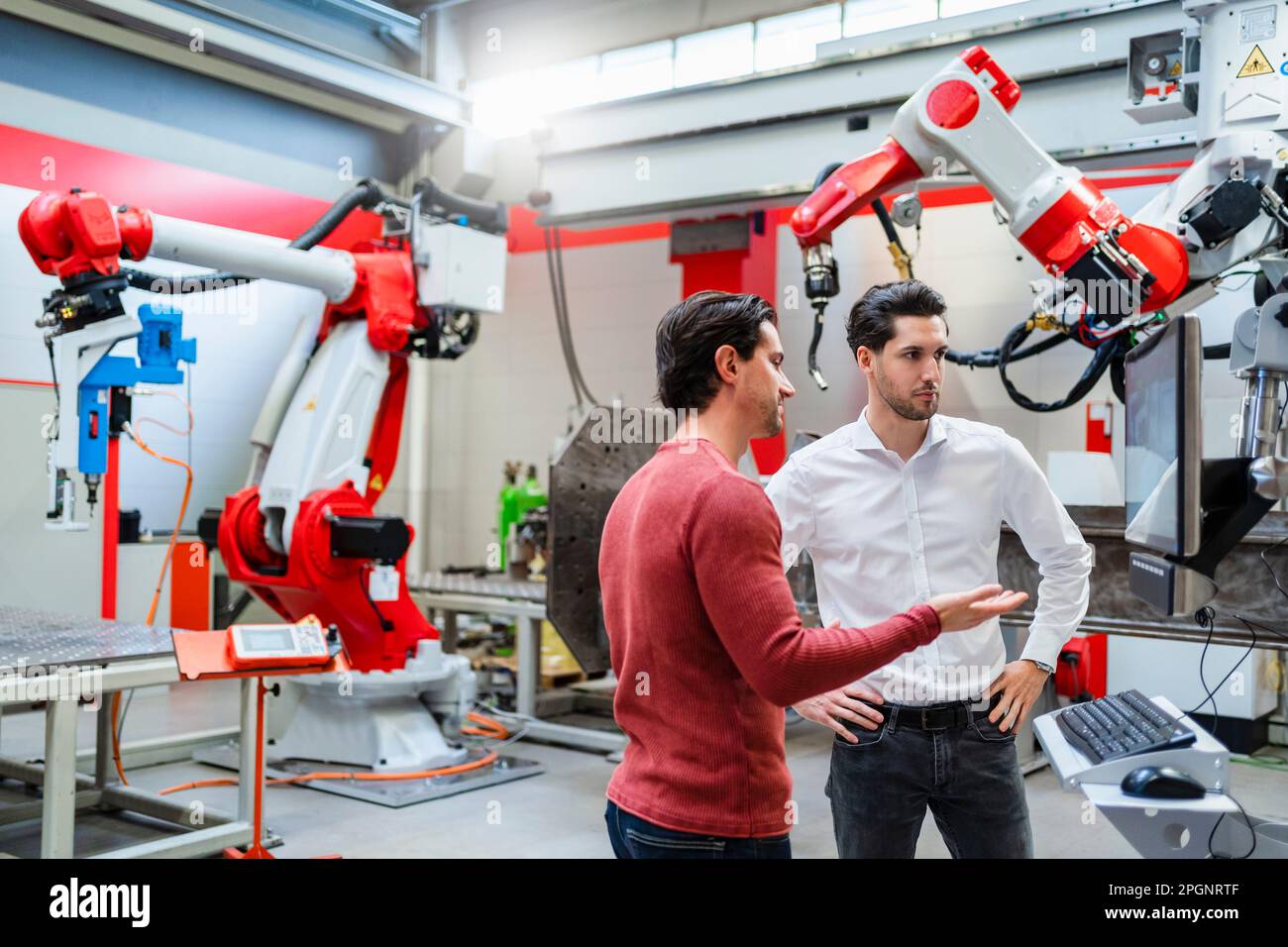 Engineers discussing over computer in robot factory Stock Photo - Alamy