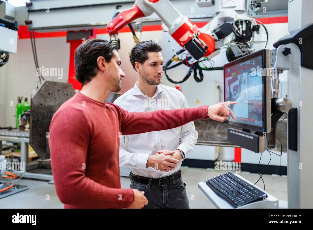 Engineer explaining colleague through computer at industry Stock Photo ...