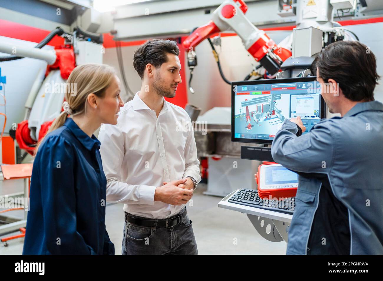 Engineer explaining colleagues over monitor at robot factory Stock Photo - Alamy