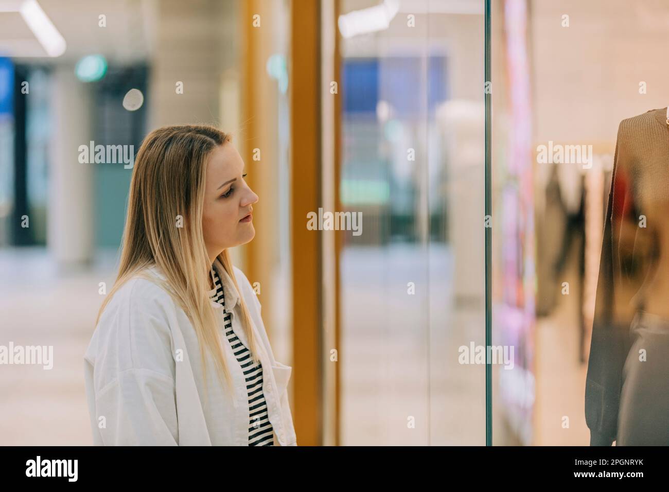 Woman looking through store window at mannequin in shopping mall Stock ...