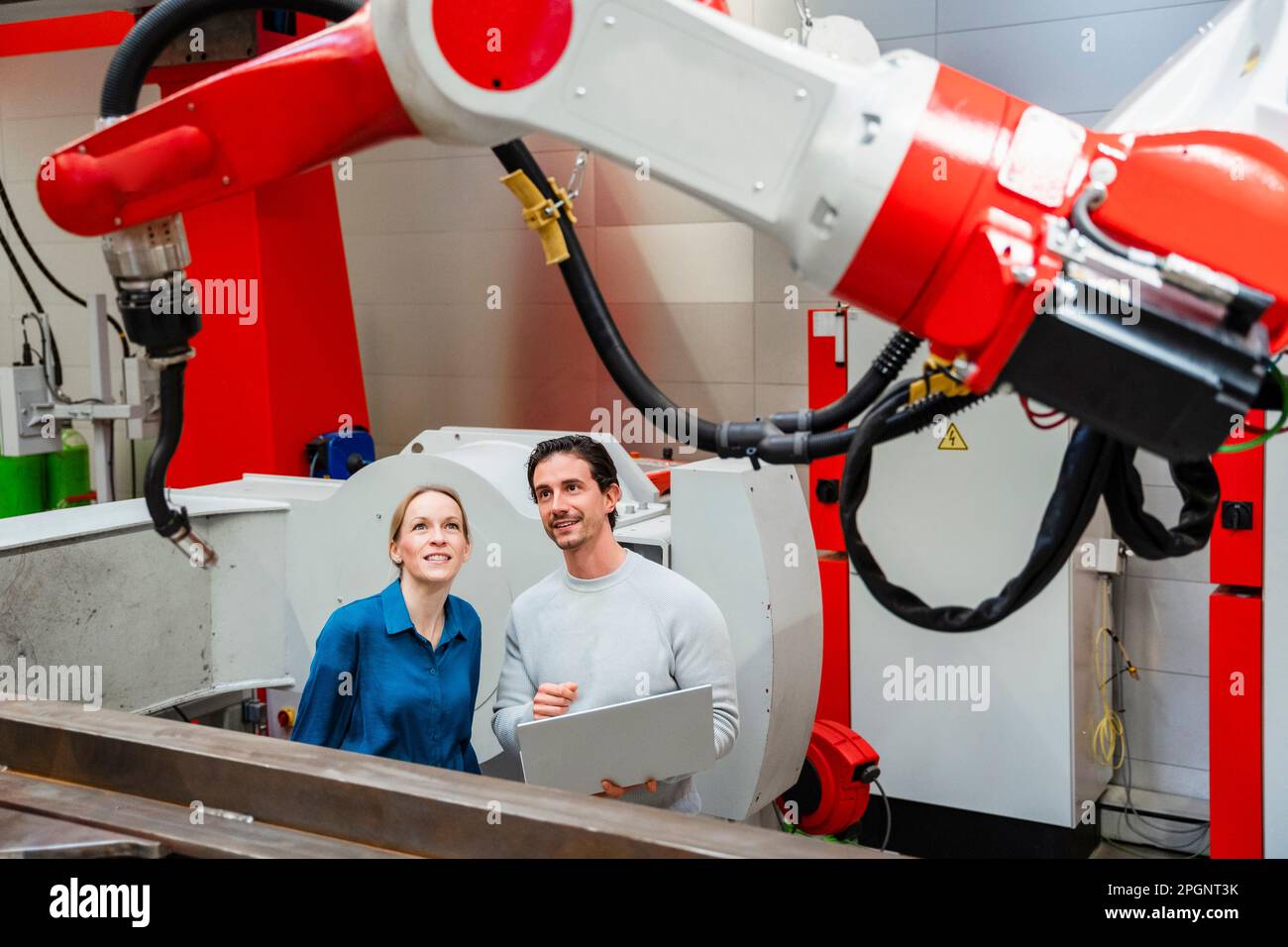 Smiling colleagues planning together in robot factory Stock Photo - Alamy