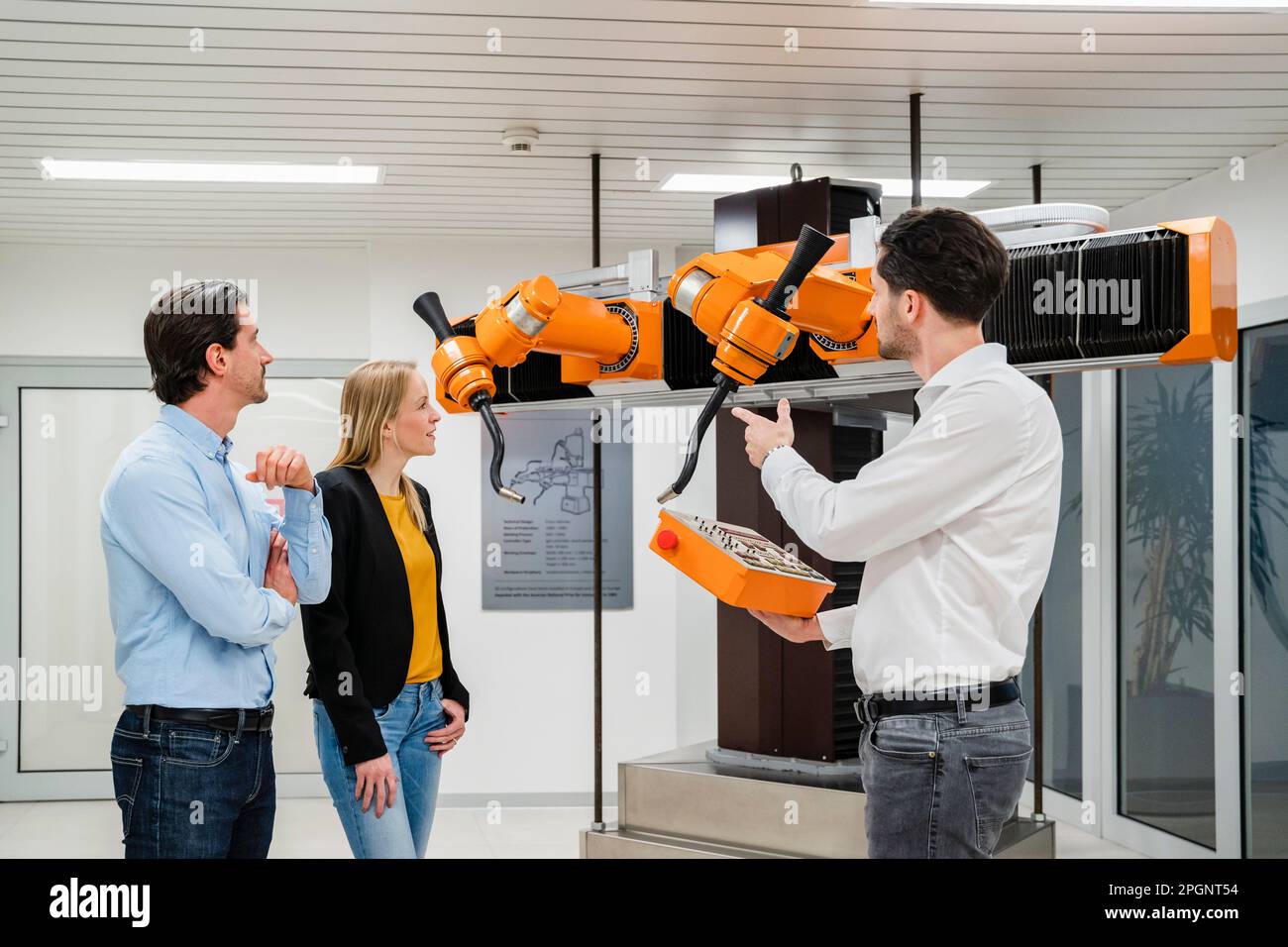 Technician operating robots near colleagues in factory Stock Photo - Alamy